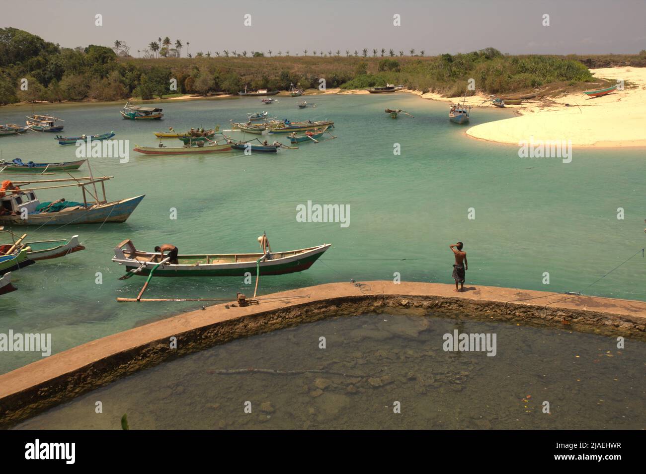 A fisherman standing on a concrete pathway on the fishing beach of Pero ...