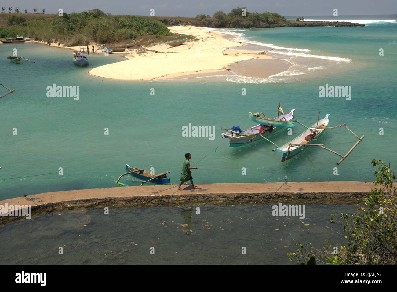 A fisherman walking on a concrete pathway on the fishing beach of Pero ...
