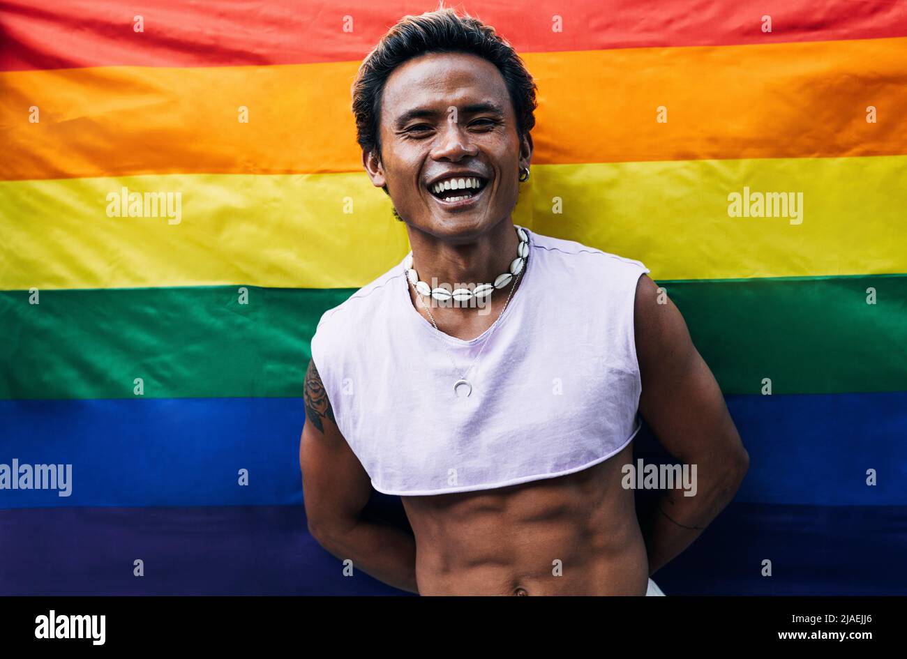 Happy guy posing on LGBT flag. Laughing male standing against rainbow ...