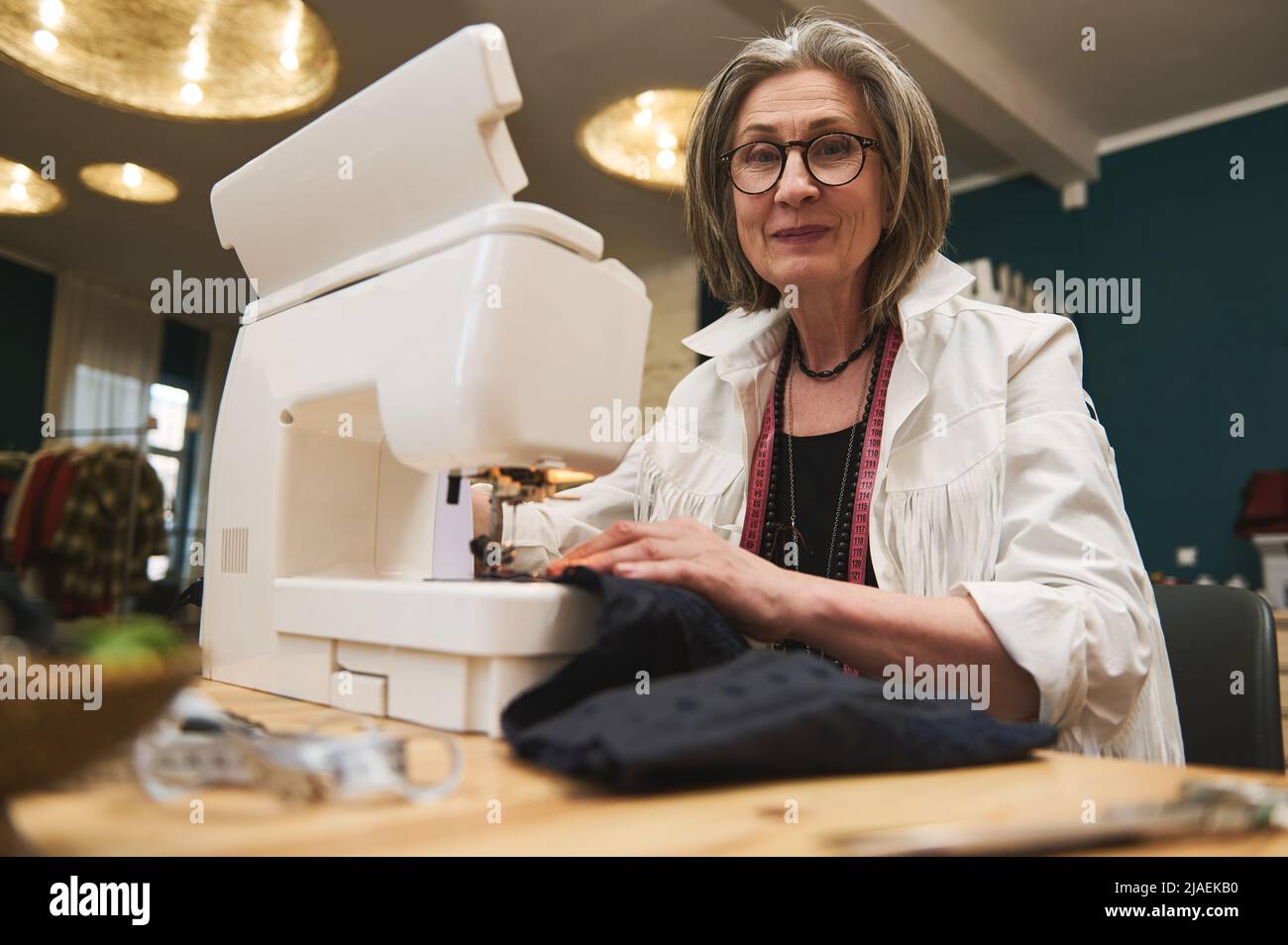 Elderly European woman dressmaker, seamstress, tailor or sewer in ...
