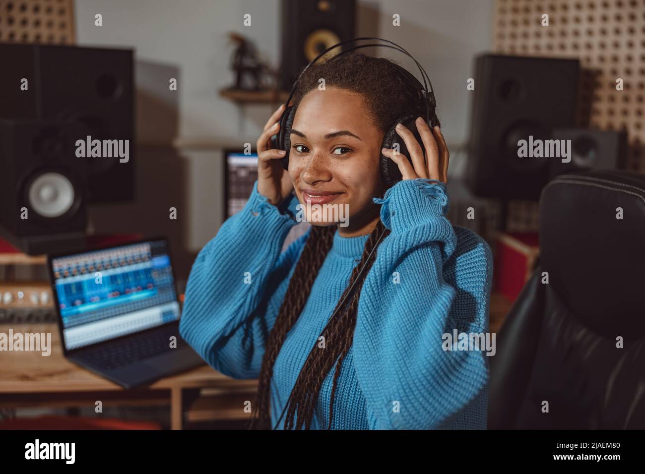 Funny multiracial anchorwoman cutely smiles, puts on headphones and ...