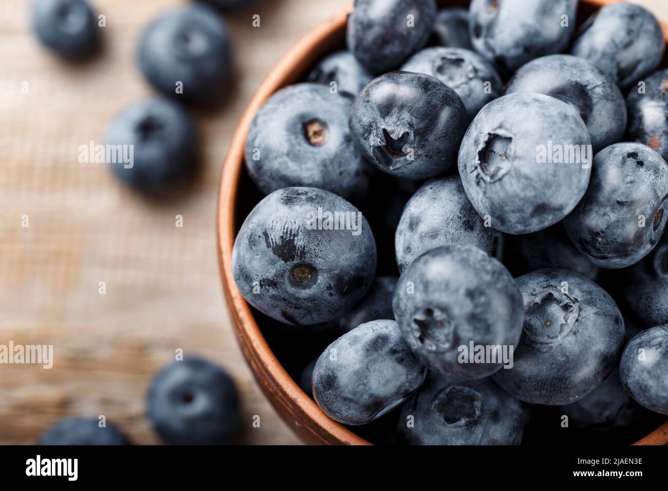 ripe blueberries in a clay plate on a brown wooden background. place ...