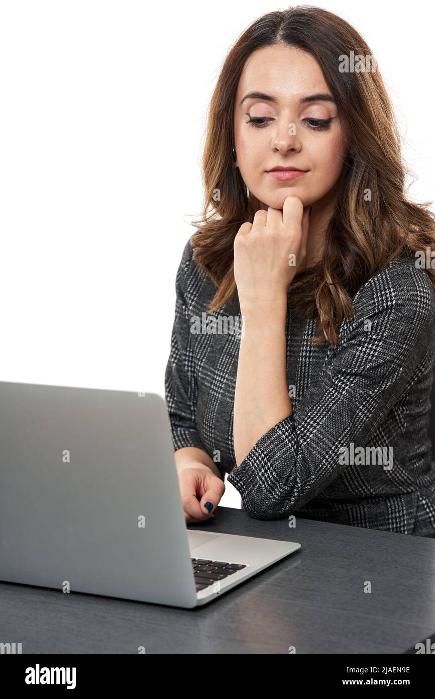 Happy successful young businesswoman at her desk, working on her laptop ...