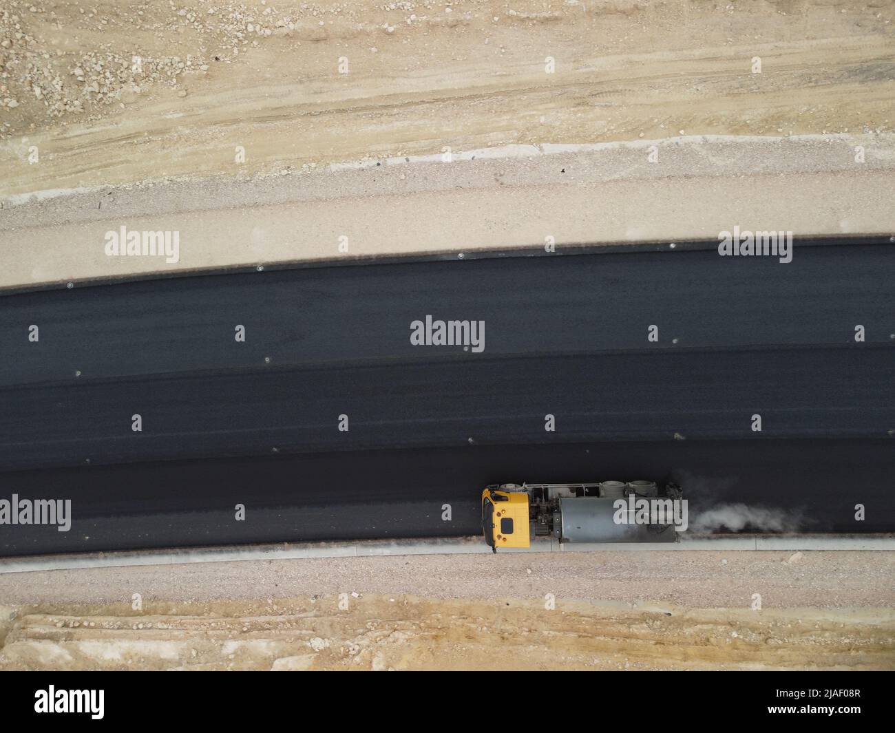 yellow truck pouring bitumen over a new road. Aerial drone shot. Road ...