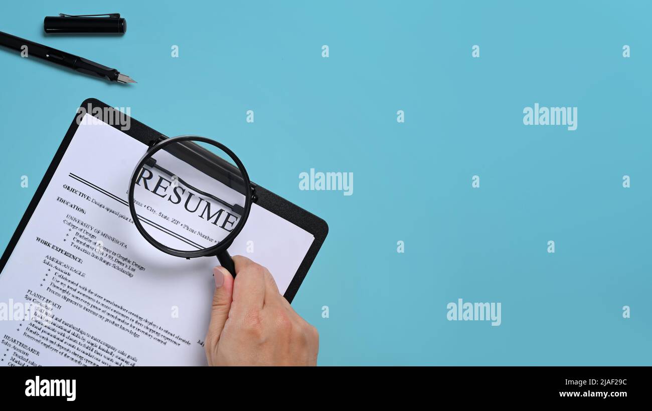 Man holding a magnifying glass over resumes of applicants. Job search ...