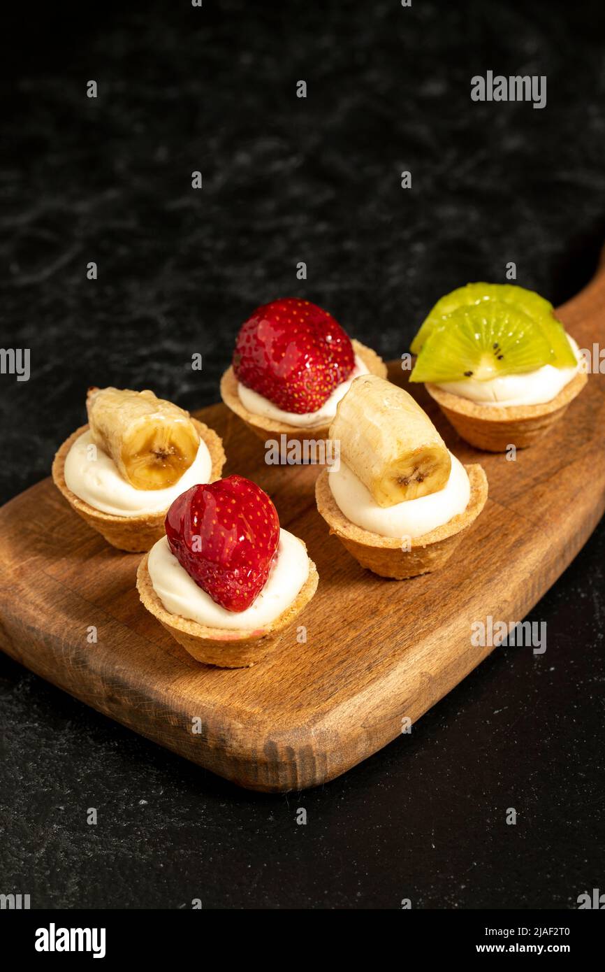 Fruit tartlet. Strawberry, kiwi and banana tartlet on a dark background ...
