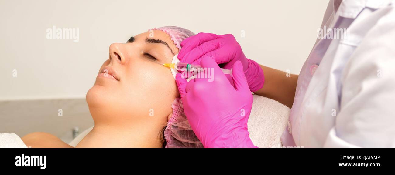 The young white woman is getting rejuvenating facial injections with ...