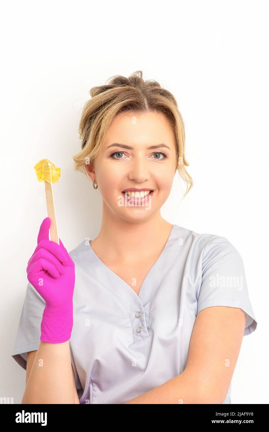 The master of sugar hair removal holds liquid yellow sugar paste, wax ...