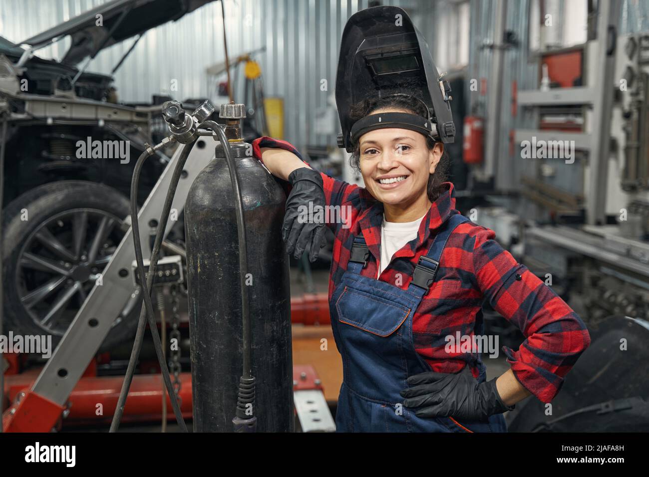 Cheerful woman auto mechanic standing in vehicle repair shop Stock ...