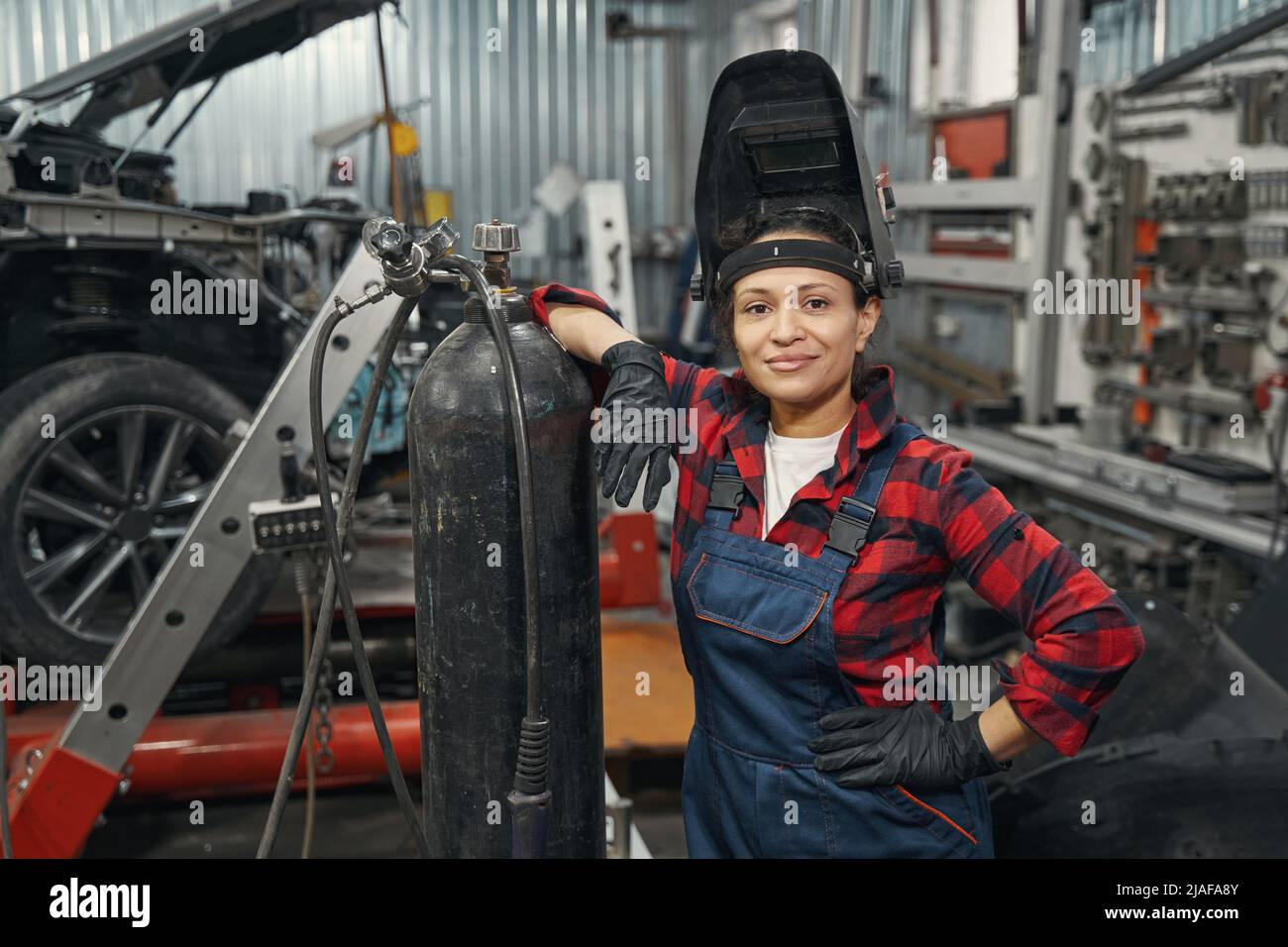 Female auto mechanic standing in car service garage Stock Photo - Alamy