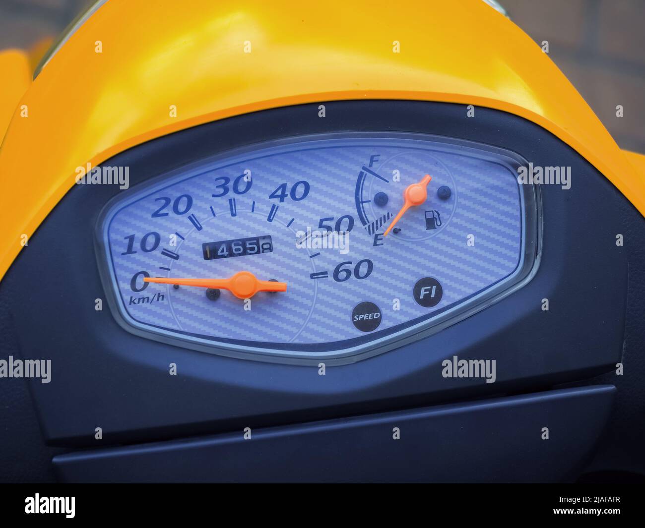 A speedometer with a dial and orange hands is located on the handlebars ...