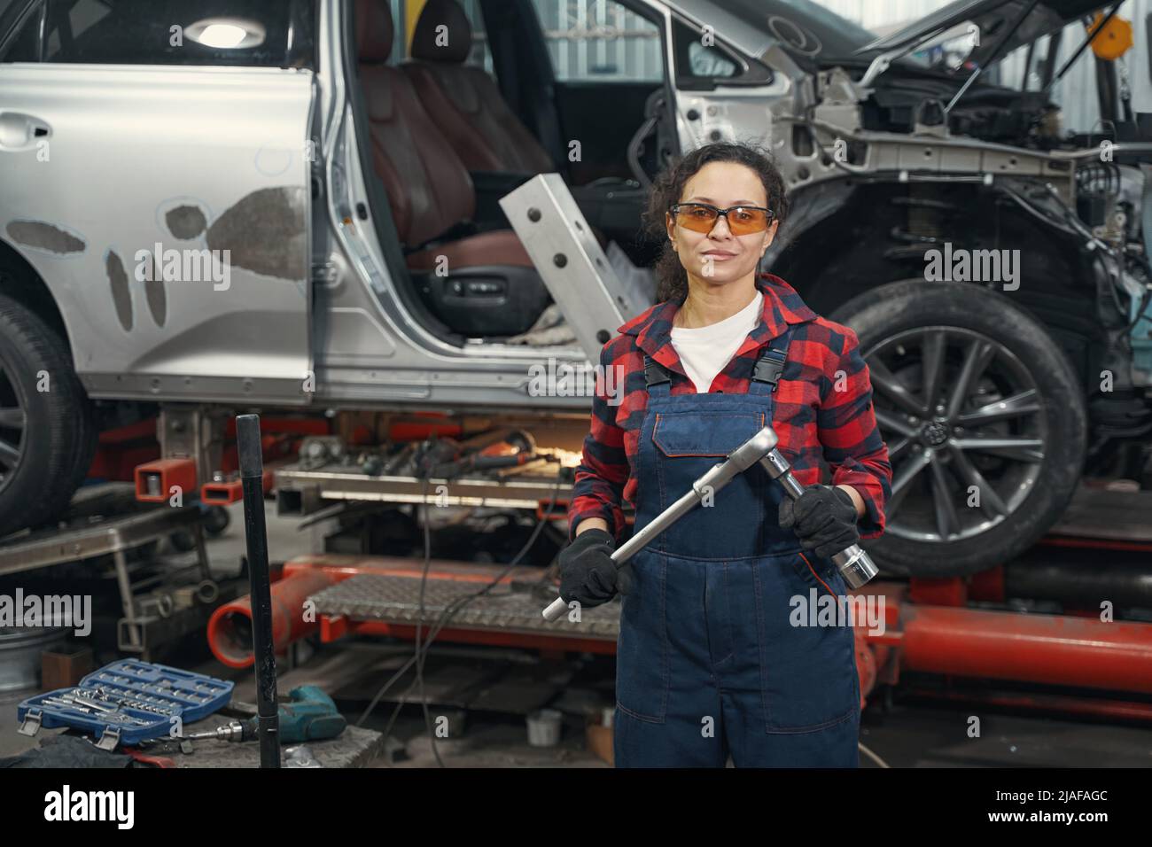 Female auto mechanic holding car repair tool in service station Stock ...