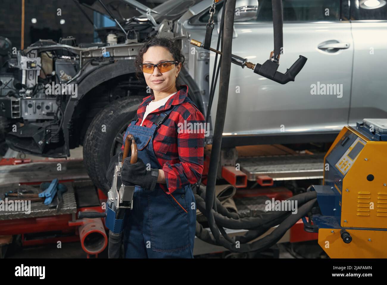 Woman auto mechanic using car repair equipment in service station Stock ...