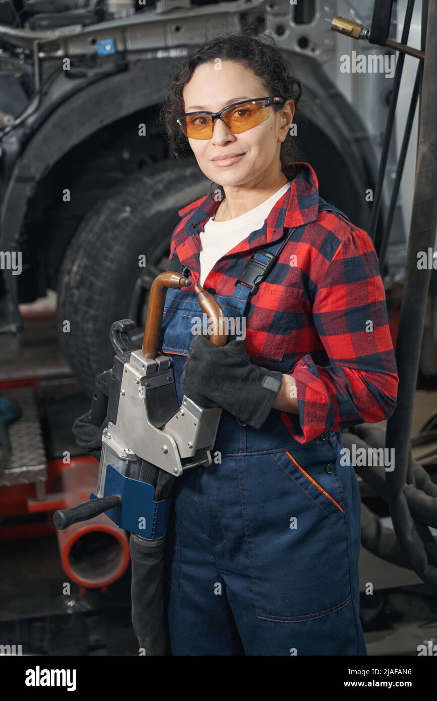 Woman car mechanic using auto repair equipment in garage Stock Photo ...