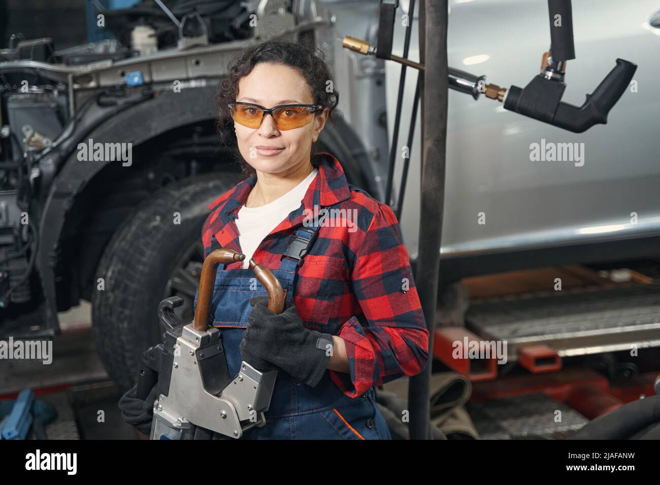 Female auto mechanic using car repair equipment in garage Stock Photo ...