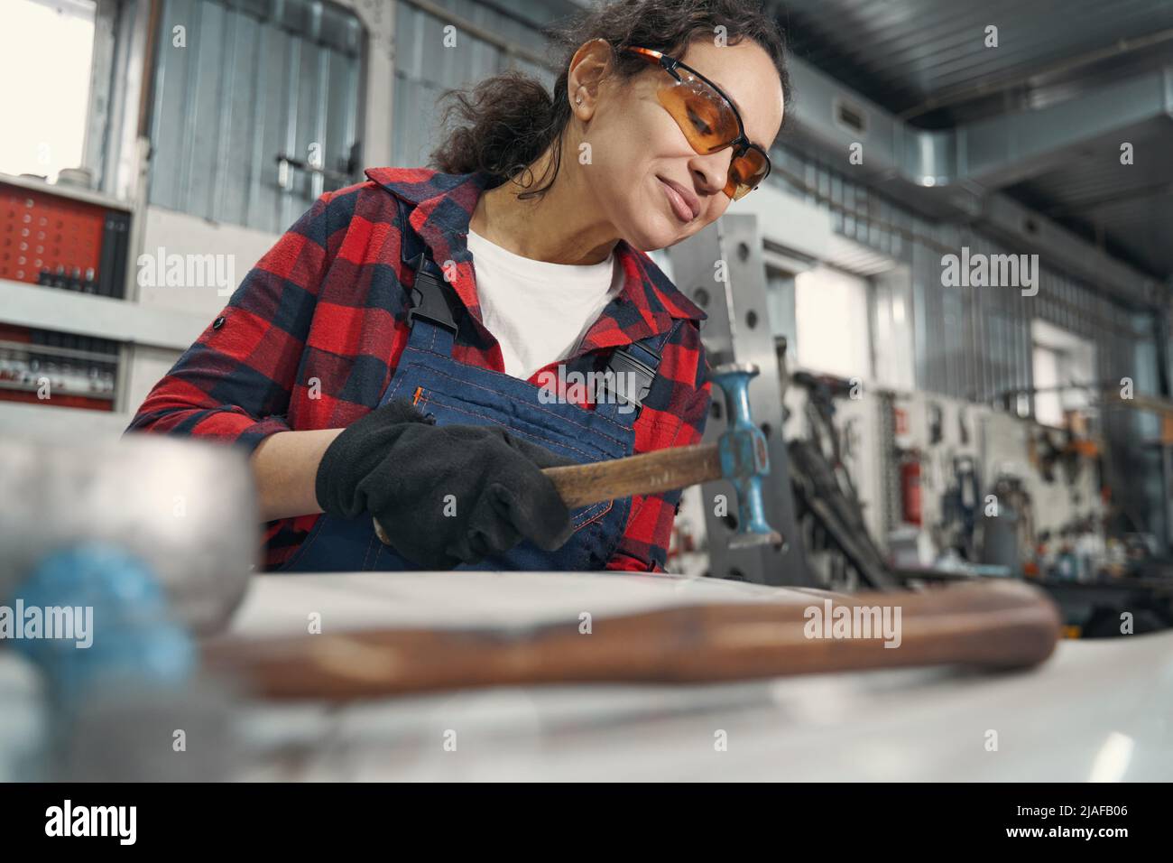 Female auto mechanic using hammer in automobile garage Stock Photo - Alamy