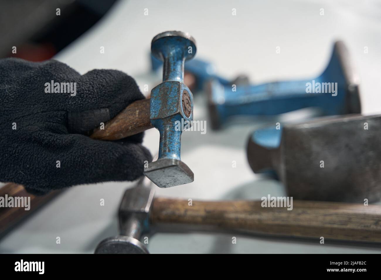 Mechanic using hammer with metal head in workshop Stock Photo - Alamy