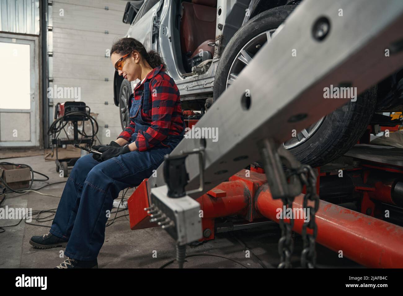 Woman car mechanic sitting by vehicle in garage Stock Photo - Alamy