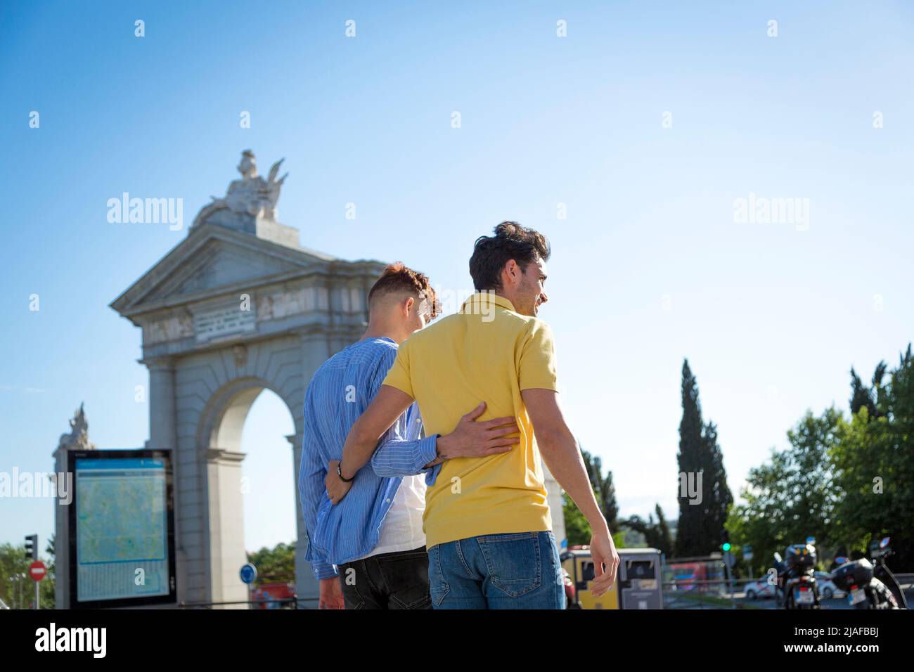 Couple of young homosexual men embraced enjoying a walk in the city ...