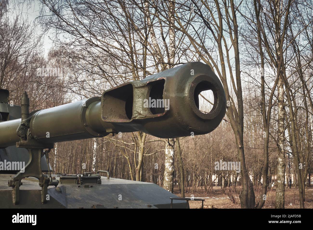 The barrel of a Russian howitzer against the background of trees close ...