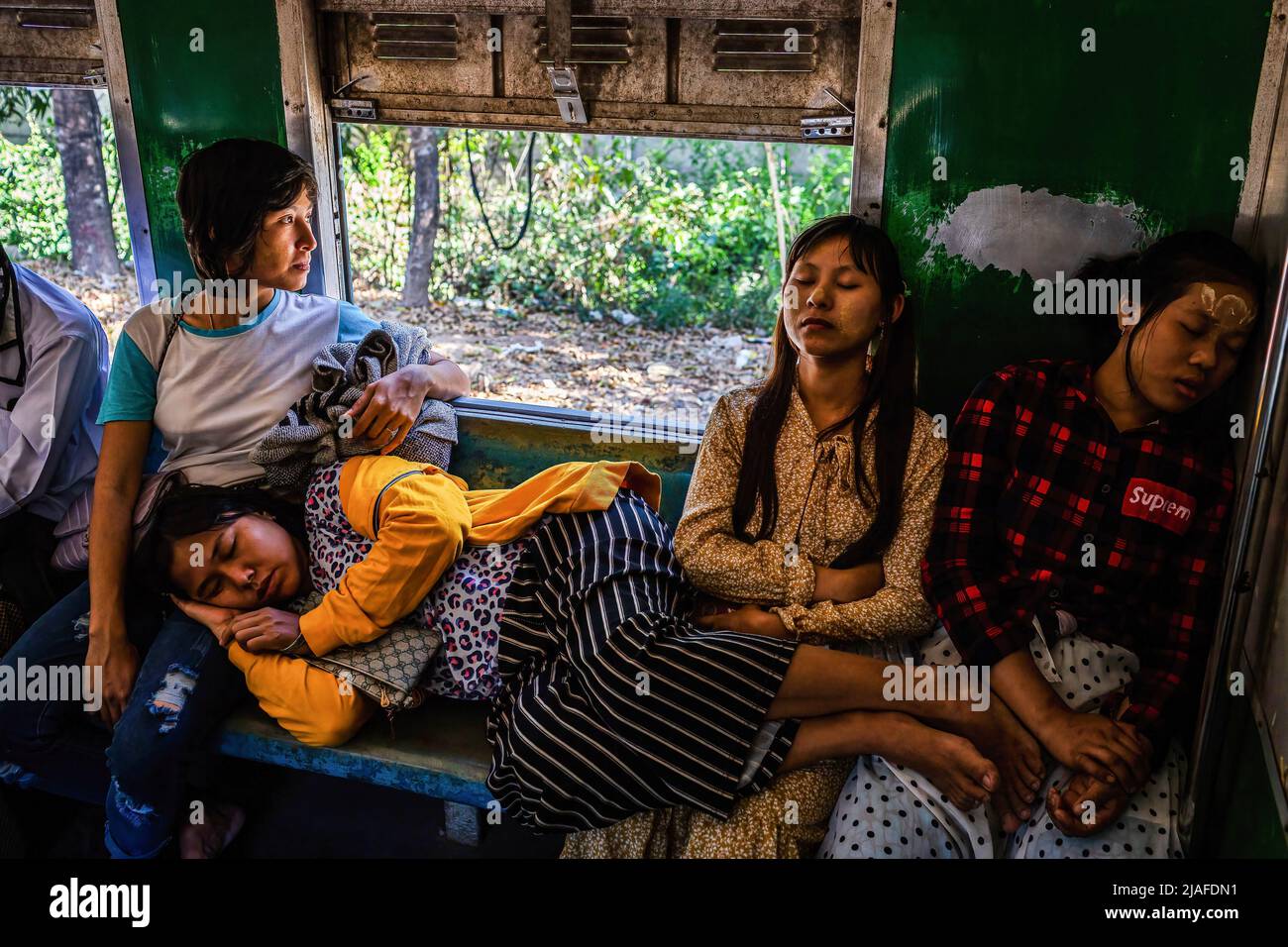 A passenger looks out of the window while other travellers take a nap inside the circular train ...