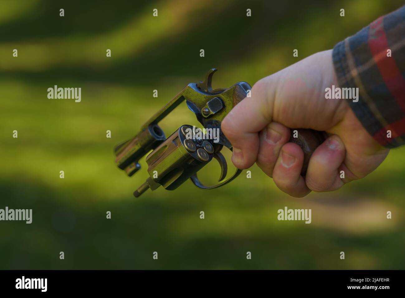 Unrecognizable man holding revolver with full cartridge in the drum ...