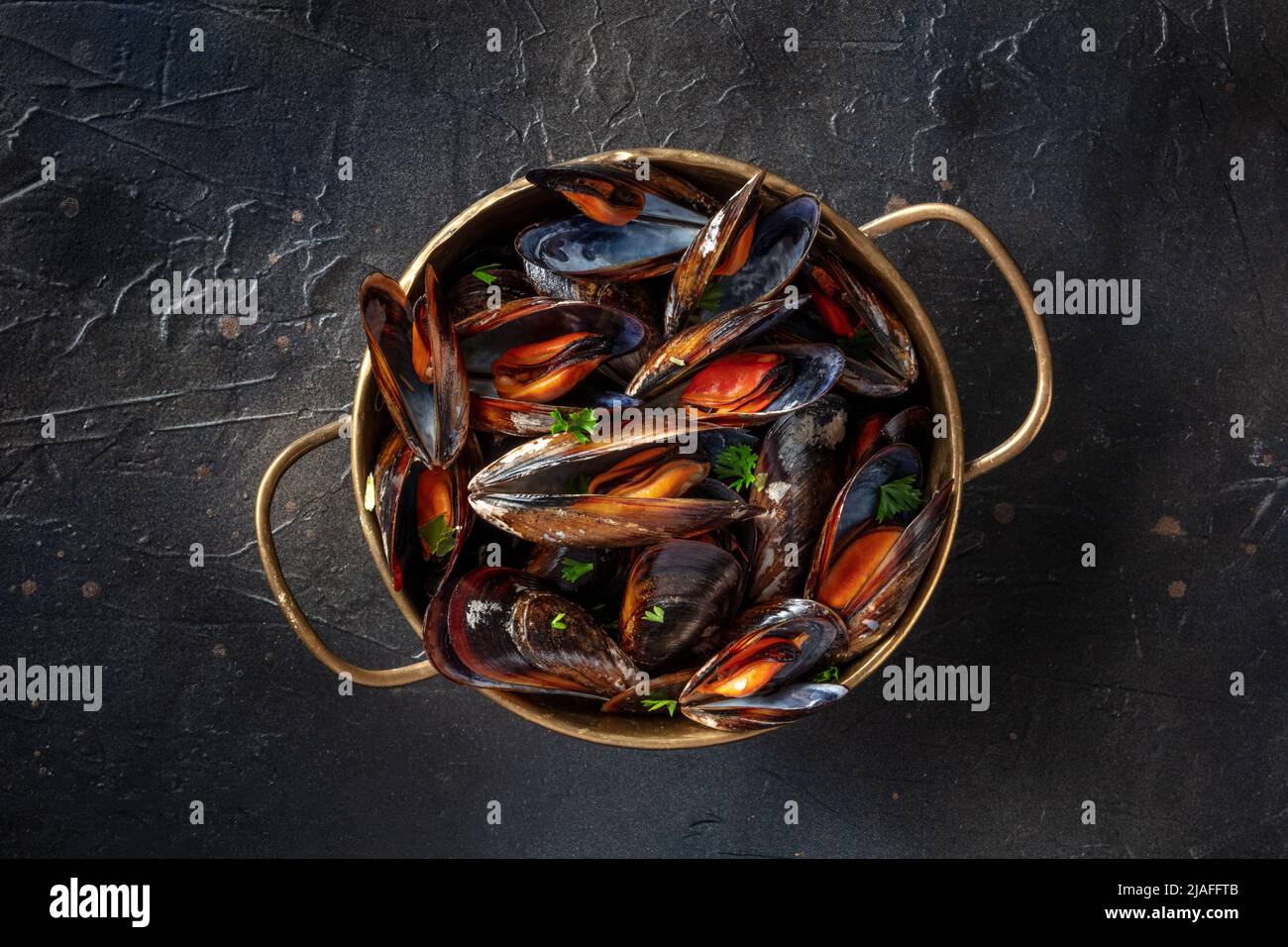 Belgian mussels in a copper pan, overhead flat lay shot on a black ...