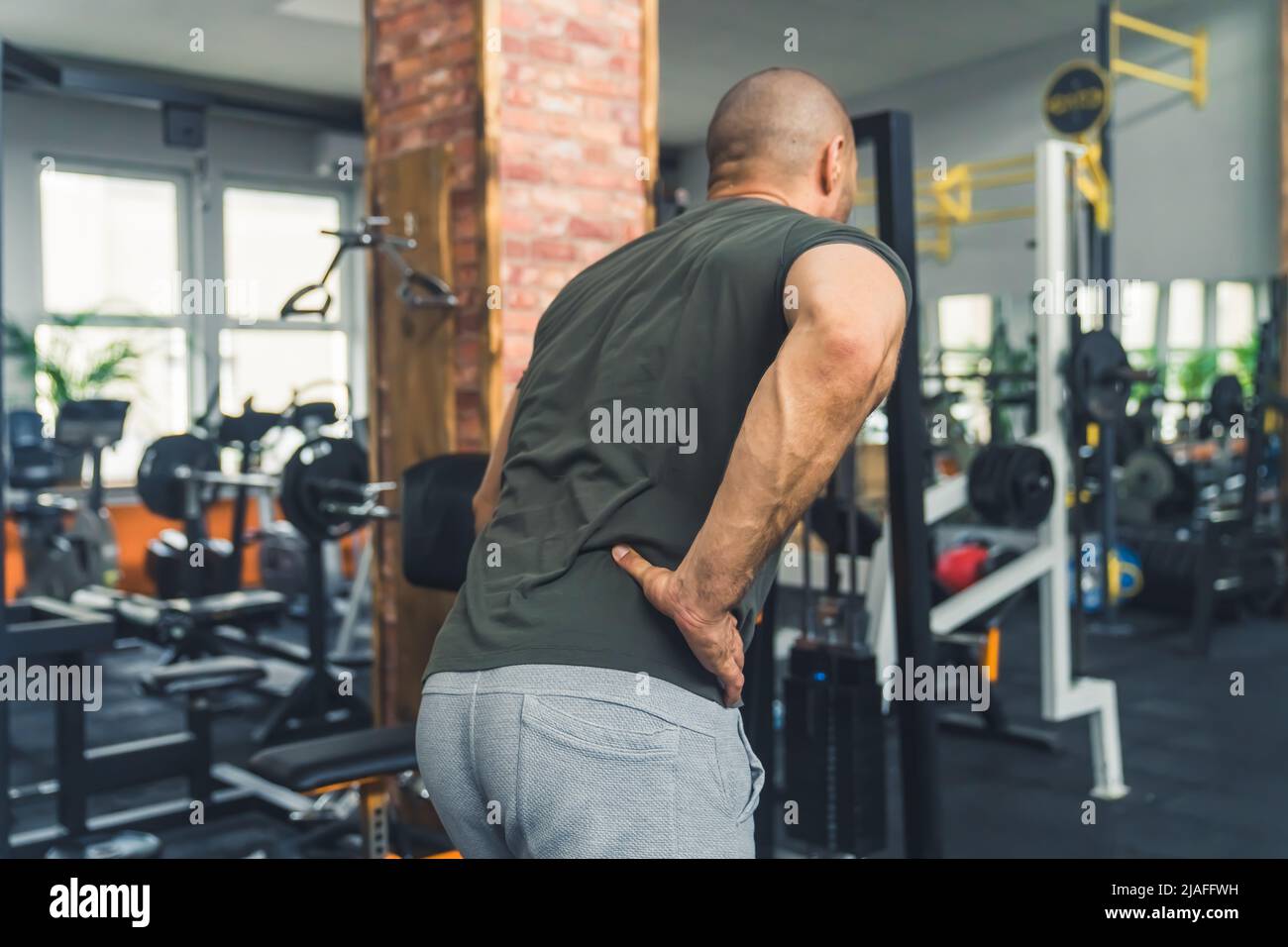 A man bruised his lower back during a workout in the gym. High quality ...