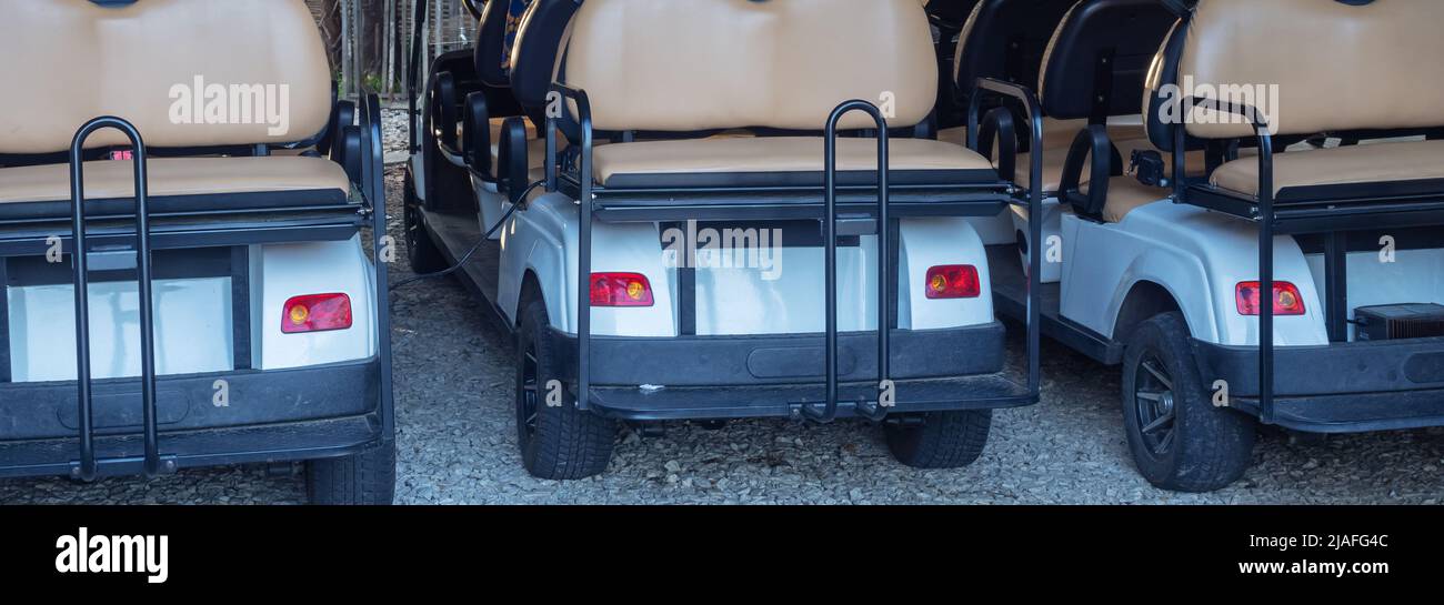 Three identical recreational electric cars are parked on gravel path in ...