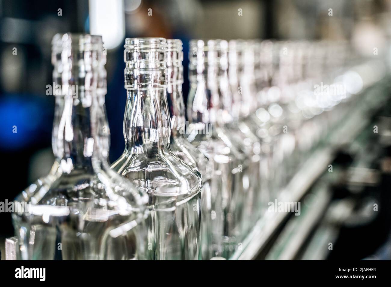 Alcohol beverage factory. Bottles on conveyor belt of bottle cleaning ...