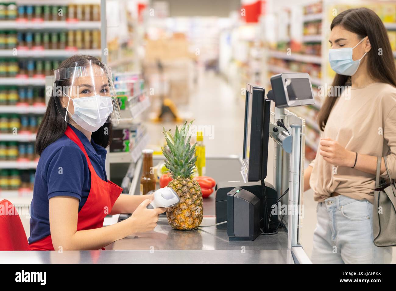 Unrecognizable supermarket cashier using computer to search for sauce ...