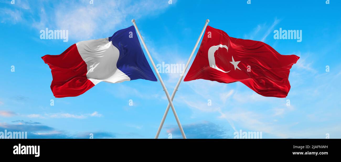 two crossed flags France and Turkey waving in wind at cloudy sky ...