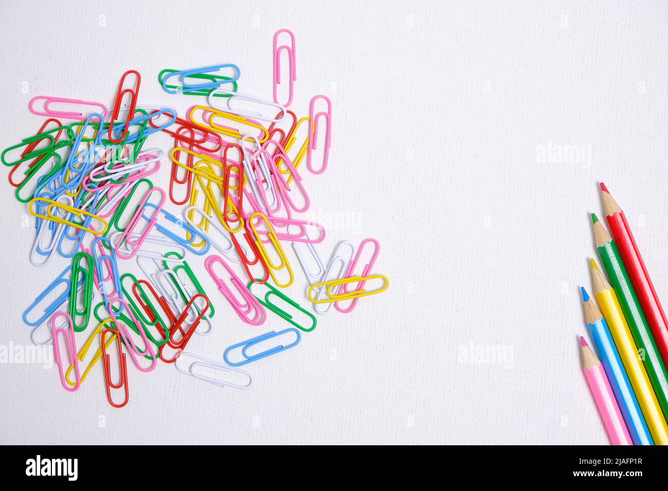 Colored pencils and paper clips white background, school supplies and ...