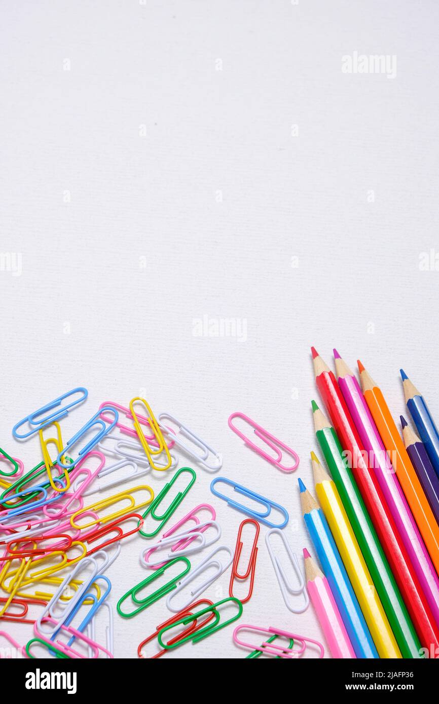 Colored pencils and paper clips white background, school supplies and ...
