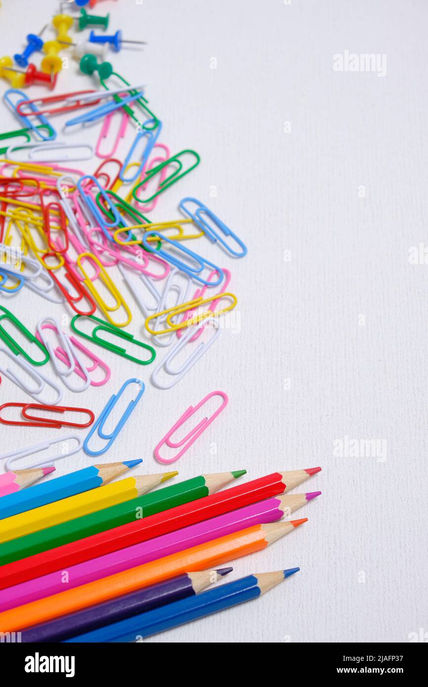 Colored pencils and paper clips white background, school supplies and ...