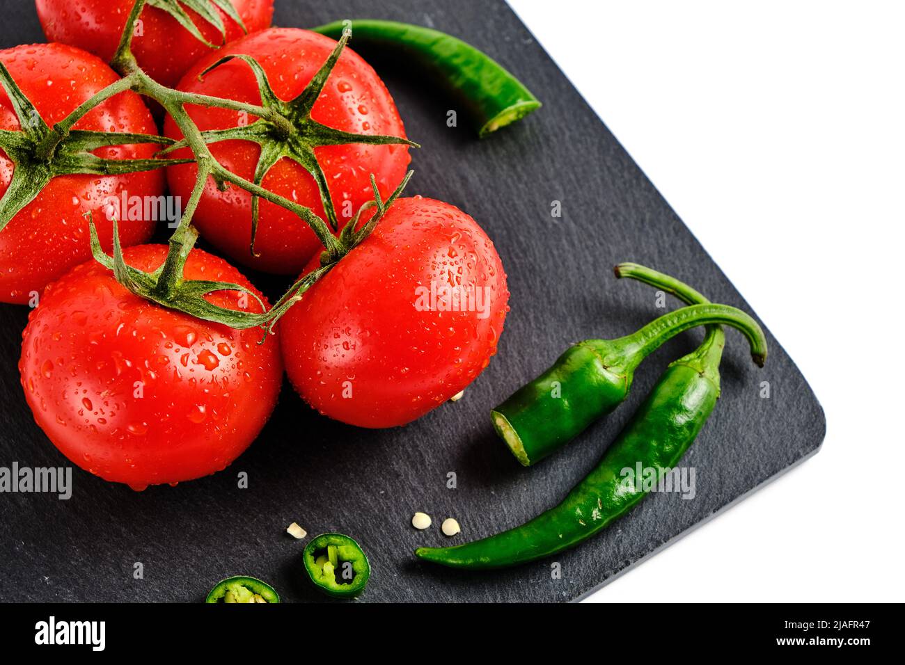 Tomatoes and pod of hot pepper on slate cutting board, isolated white ...