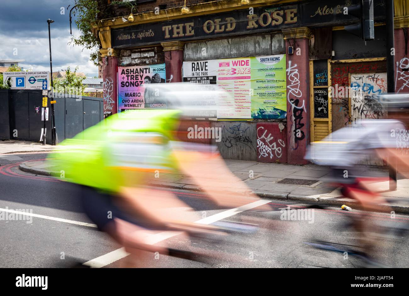 Two cyclists participating in RideLondon 2022 pass a derelict pub ...