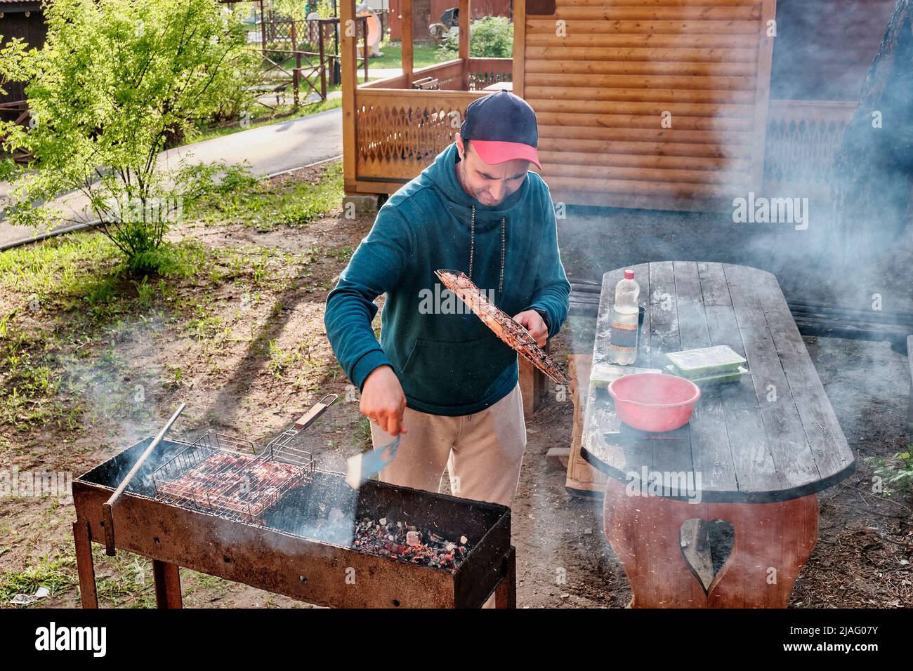 Middle aged man cooking chicken meat on barbecue grill in backyard ...