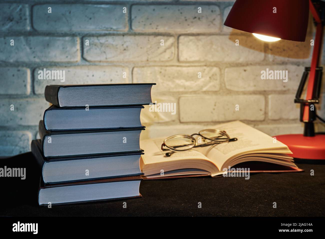 Books, glasses and a table lamp on a wall background. A table lamp ...