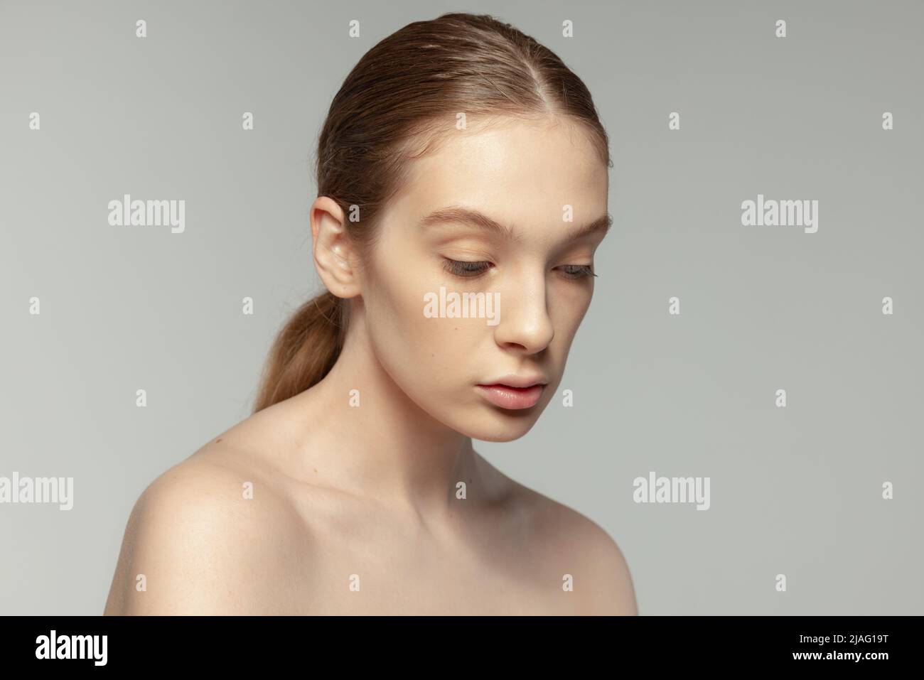 Portrait of young girl with no make uo clear face isolated over grey ...