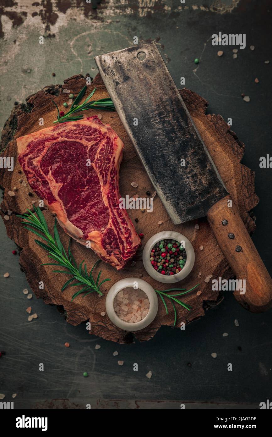 top view of bloody red meat with salt and pepper and cleaver knife on ...