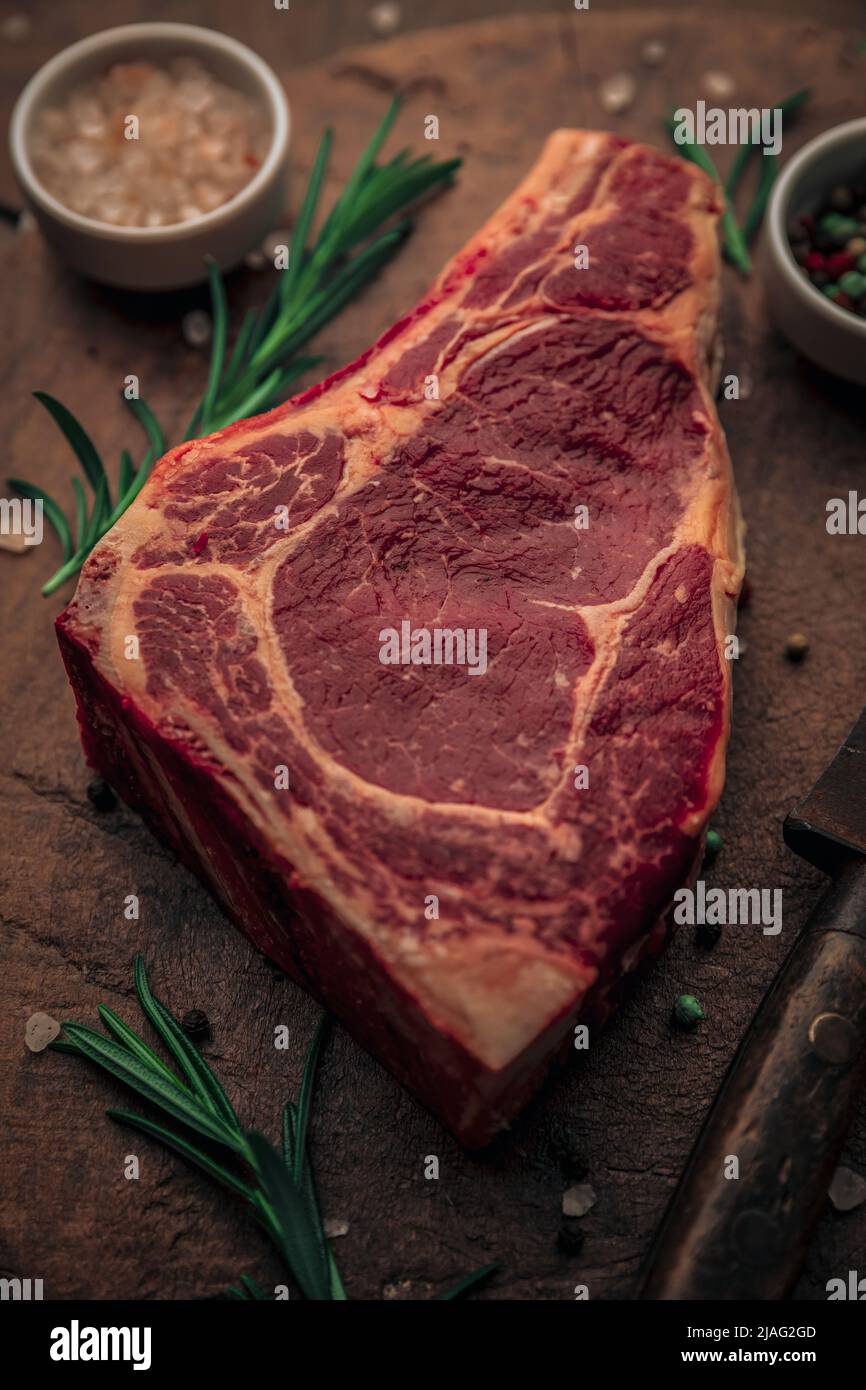 bloody beef steak with rosemary and bowls of salt and pepper on top of ...