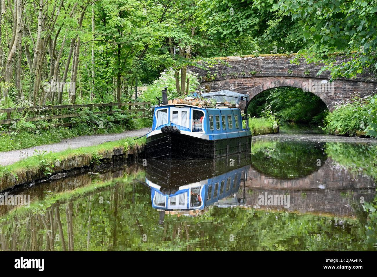 A narrowboat and its reflection on the Peak Forest Canal in New Mills ...