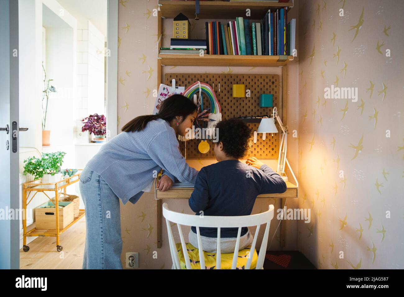 Side view of sister helping brother while studying at home Stock Photo ...