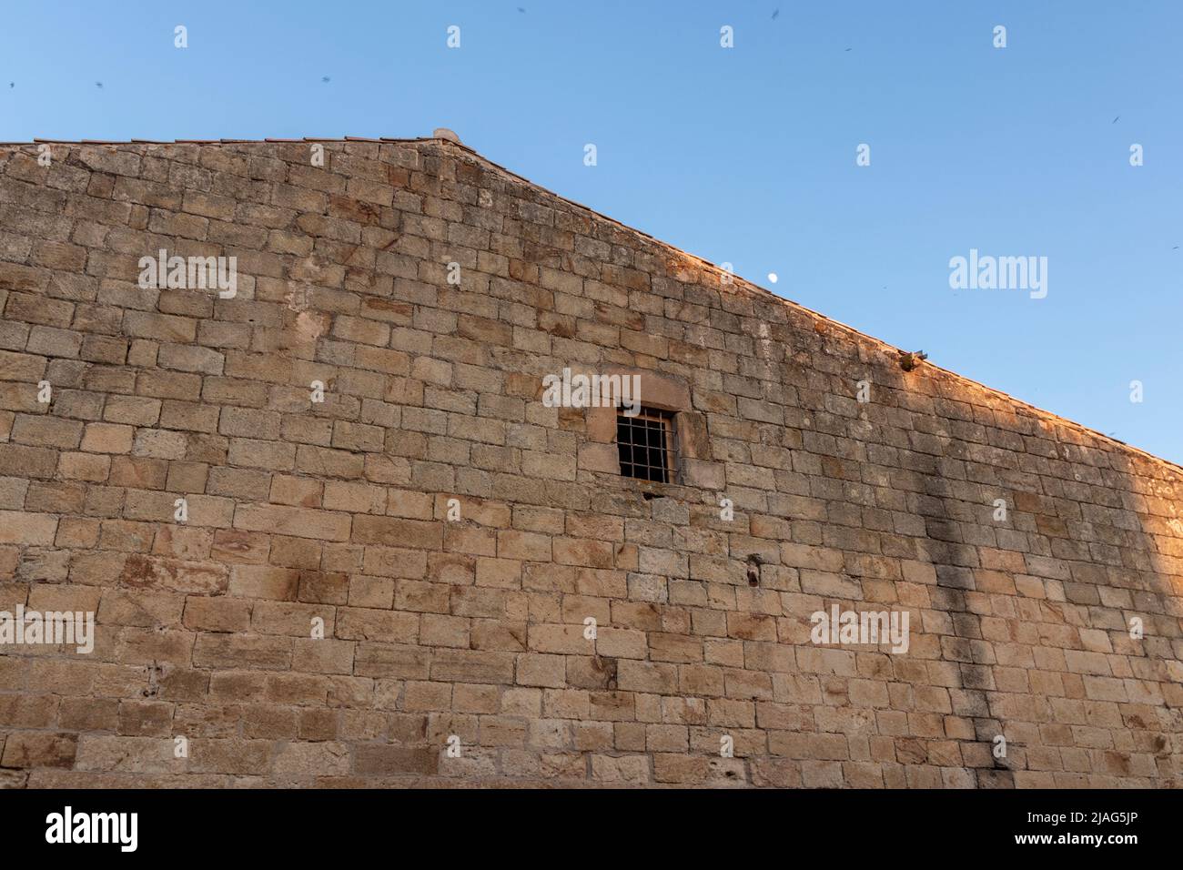 stone facade with a small barred window in the village of pals Stock ...