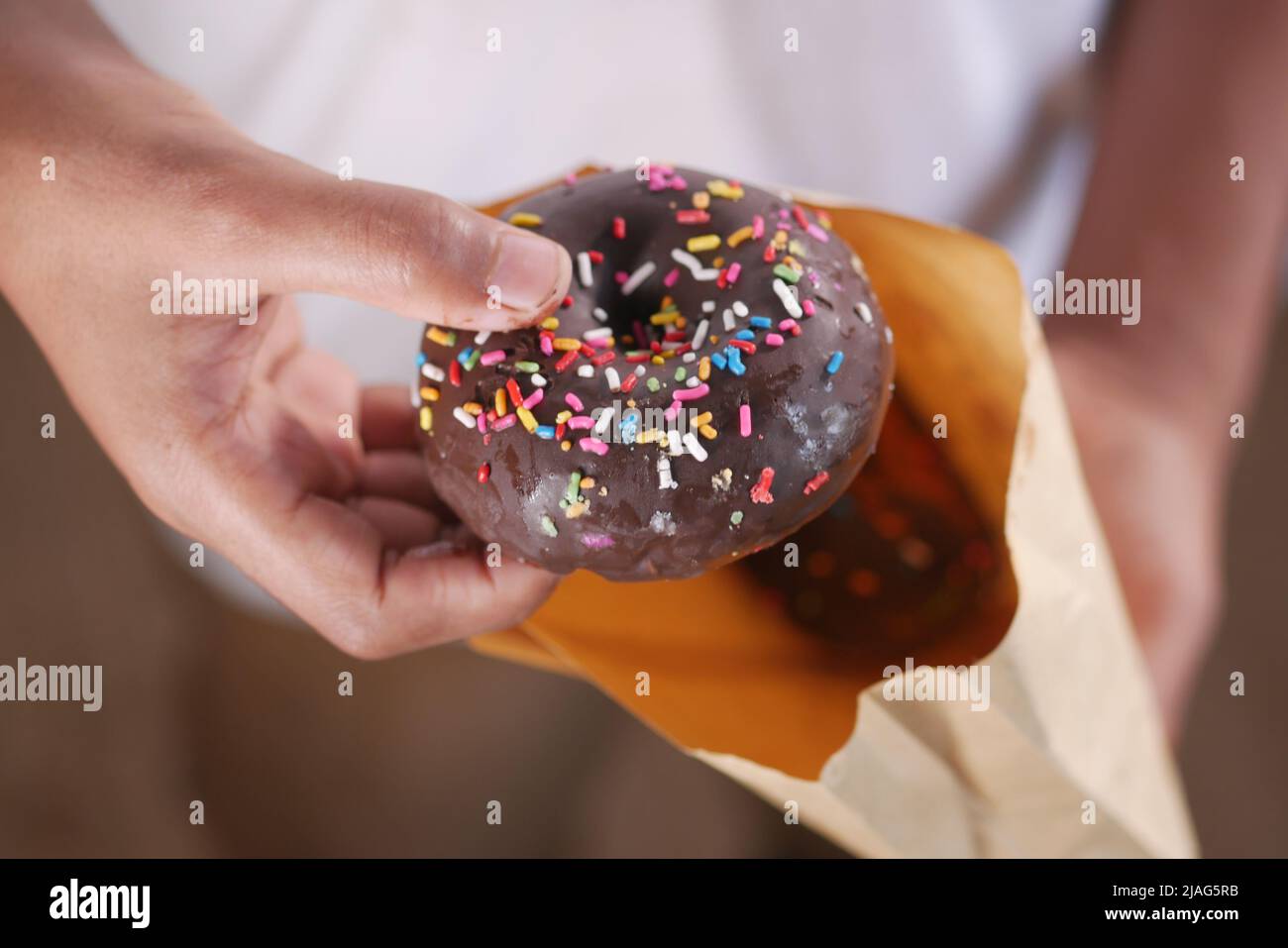young man taking donuts out from a packet Stock Photo - Alamy