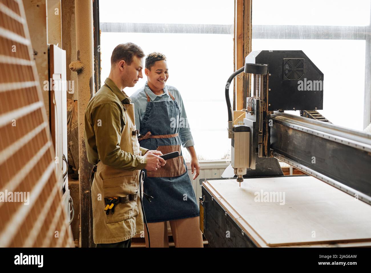 Side view portrait of two carpenters operating CNC laser machine in ...