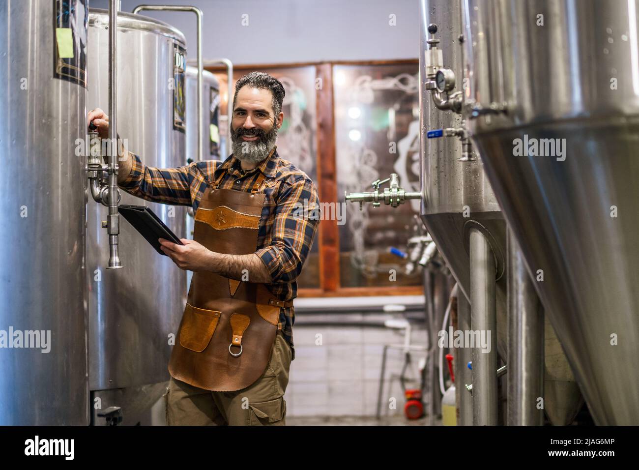 Man is working at craft beer factory. He is operating machinery in ...