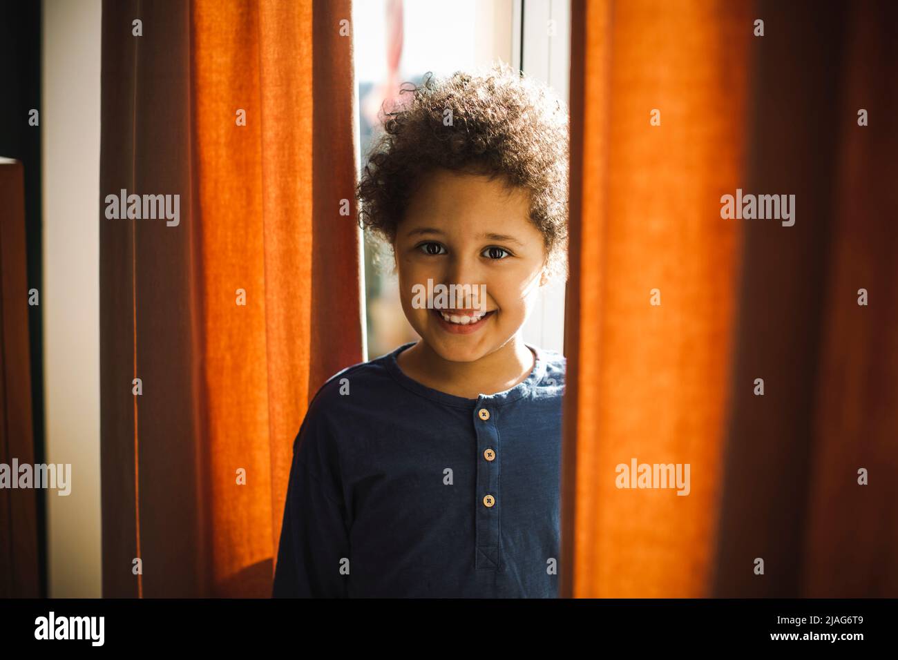 Portrait of smiling boy standing behind curtain at home Stock Photo - Alamy
