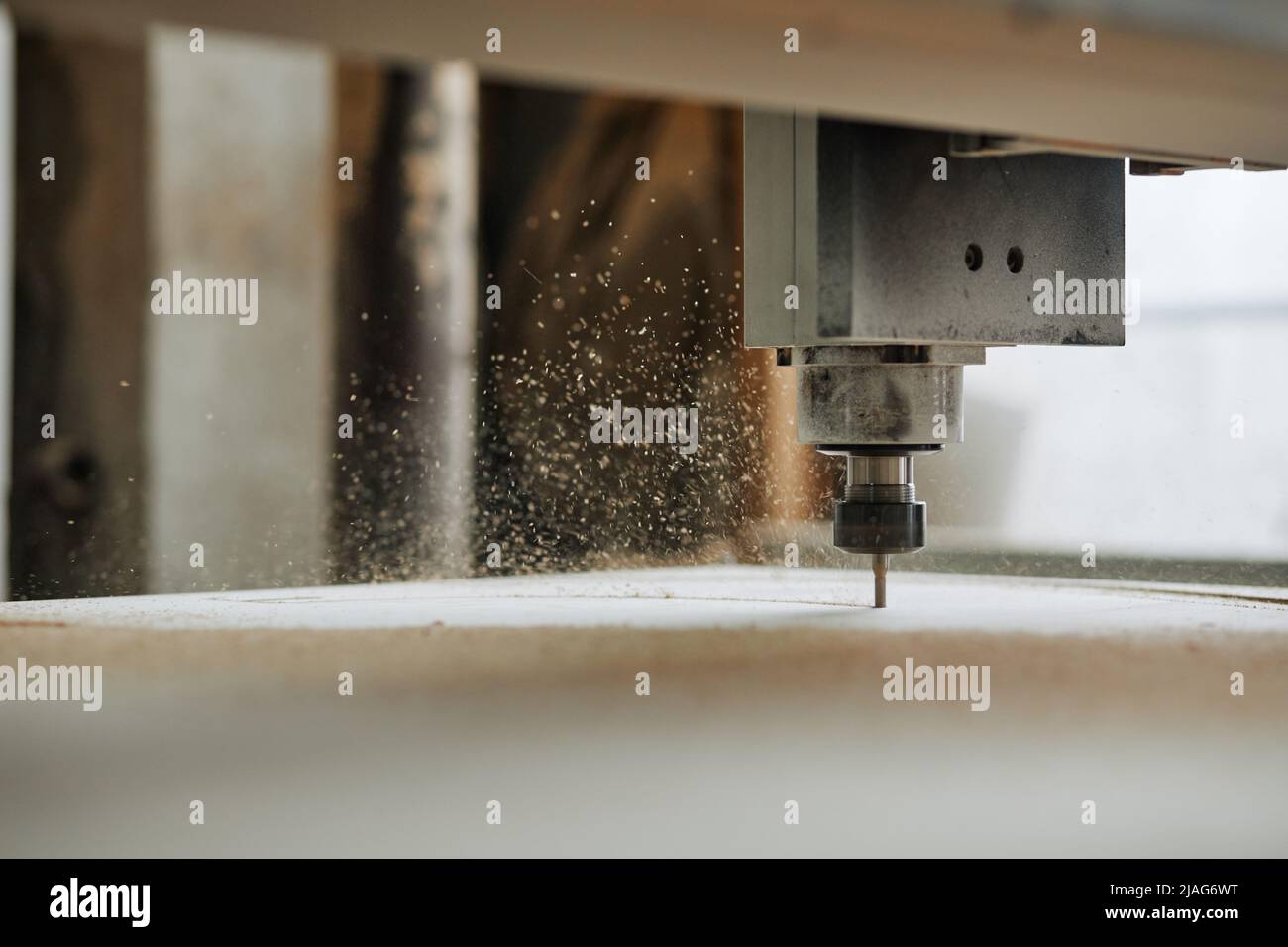 Macro shot of CNC engraving machine cutting wood in automated production workshop with sawdust ...